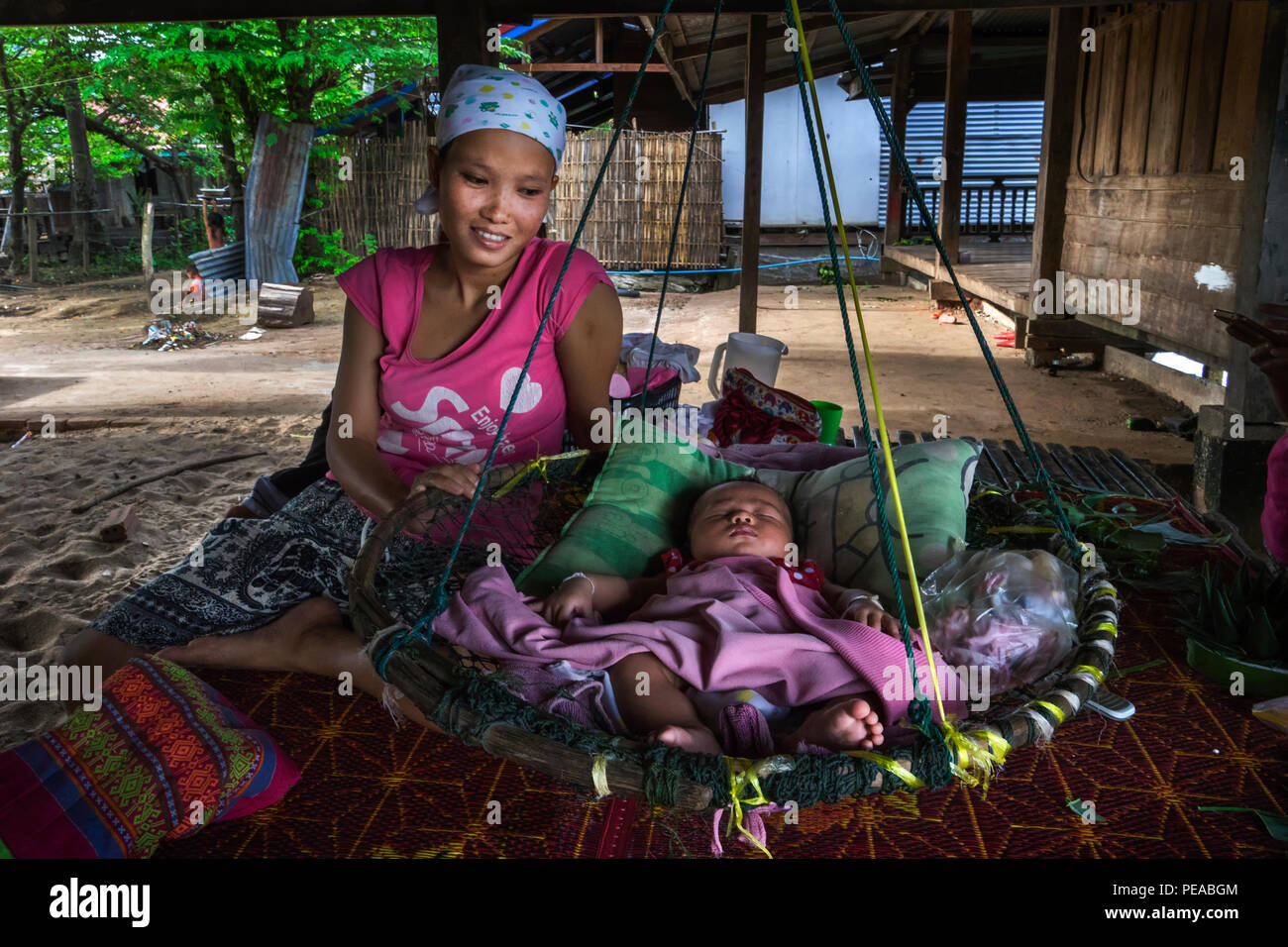 A baby is rocked to sleep by a happy mother in Southern Laos ethnic ...