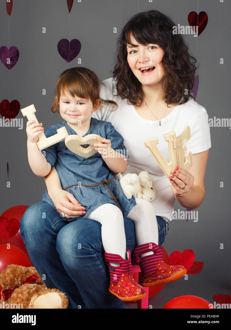 Portrait of young Caucasian mother sitting on chair with baby girl ...