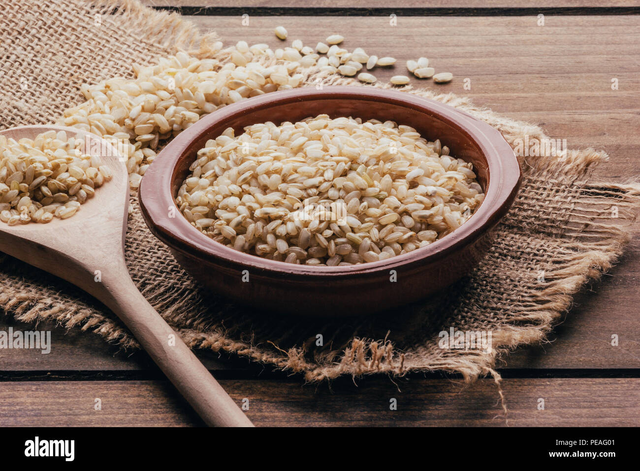 Full container with brown rice, rustic style Stock Photo - Alamy