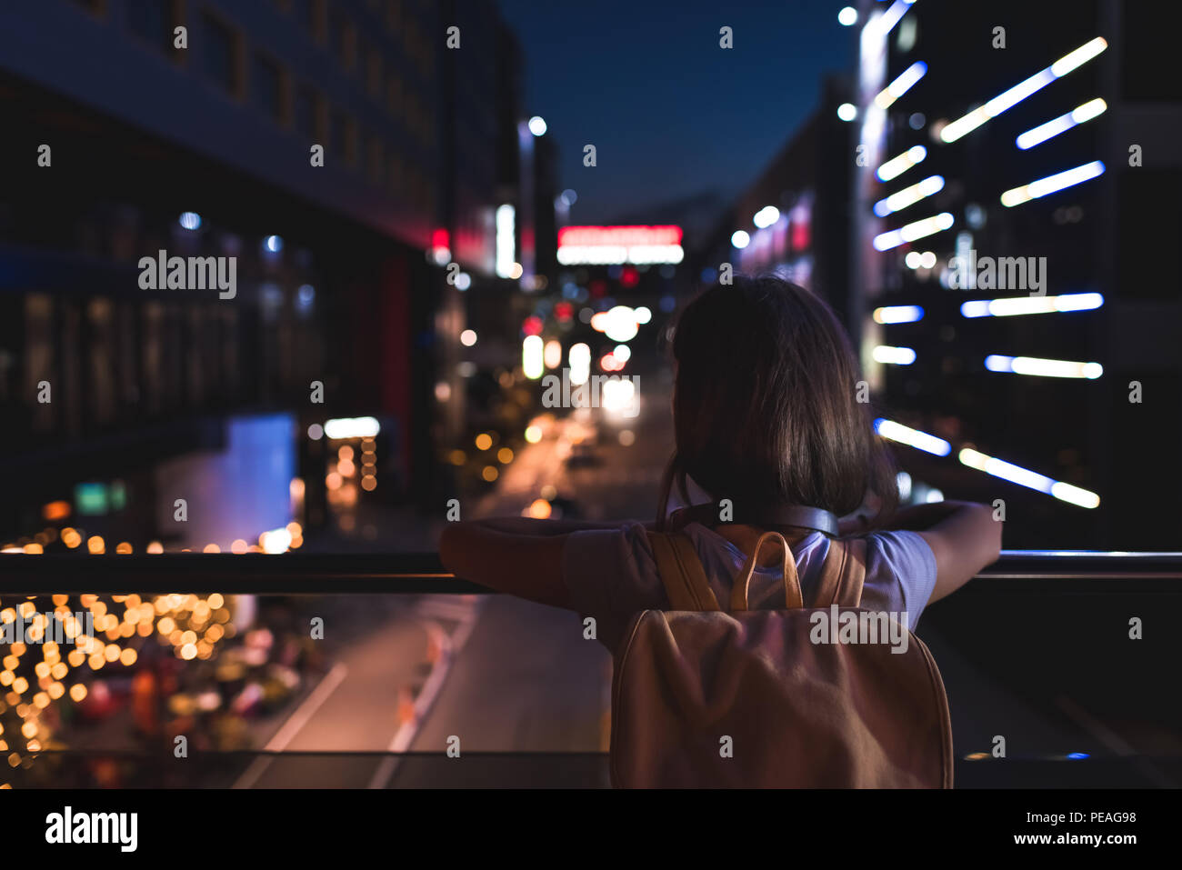 back view of woman with backpack standing on street and looking at ...