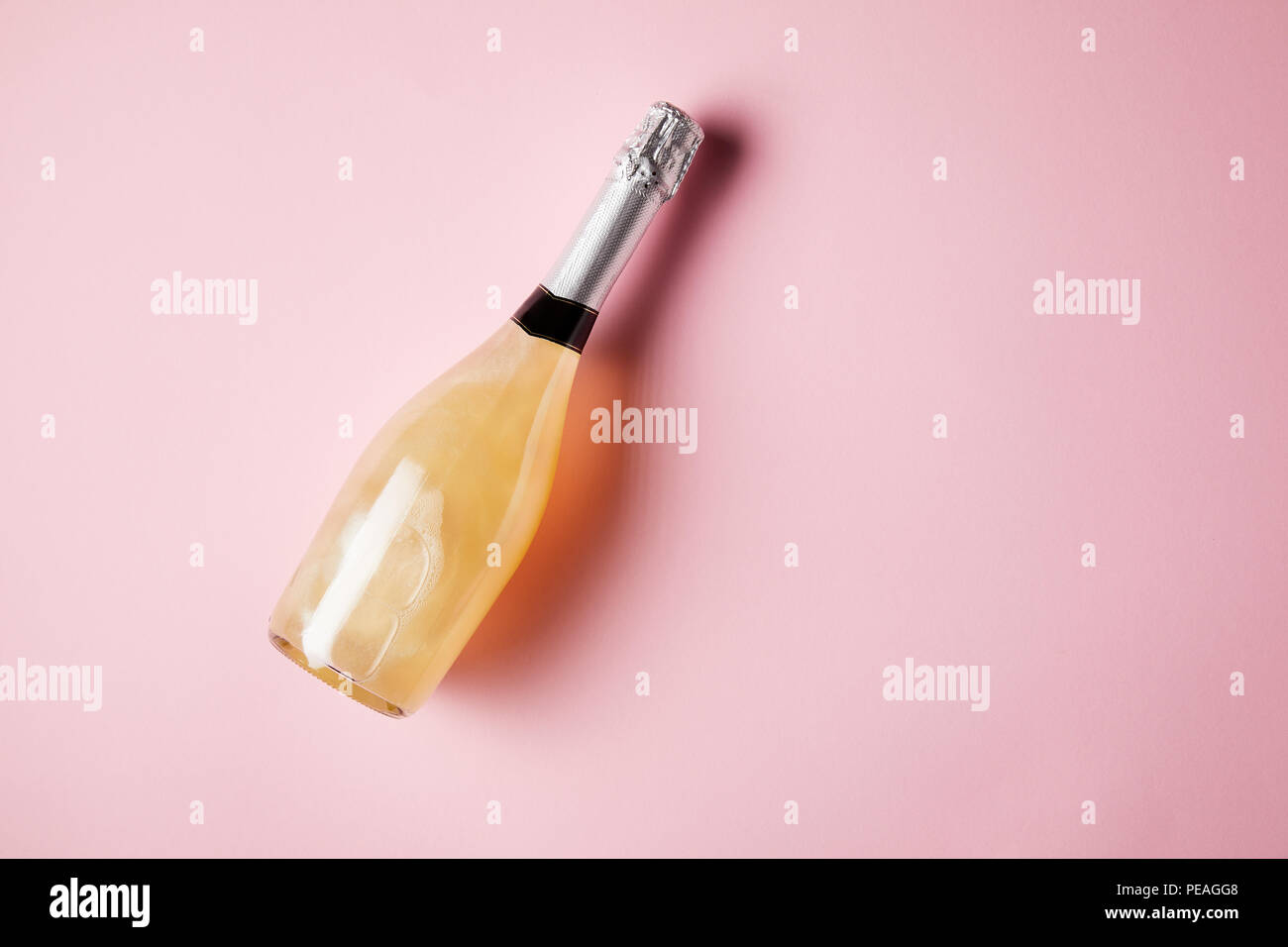 elevated view of bottle of champagne on pink surface Stock Photo - Alamy