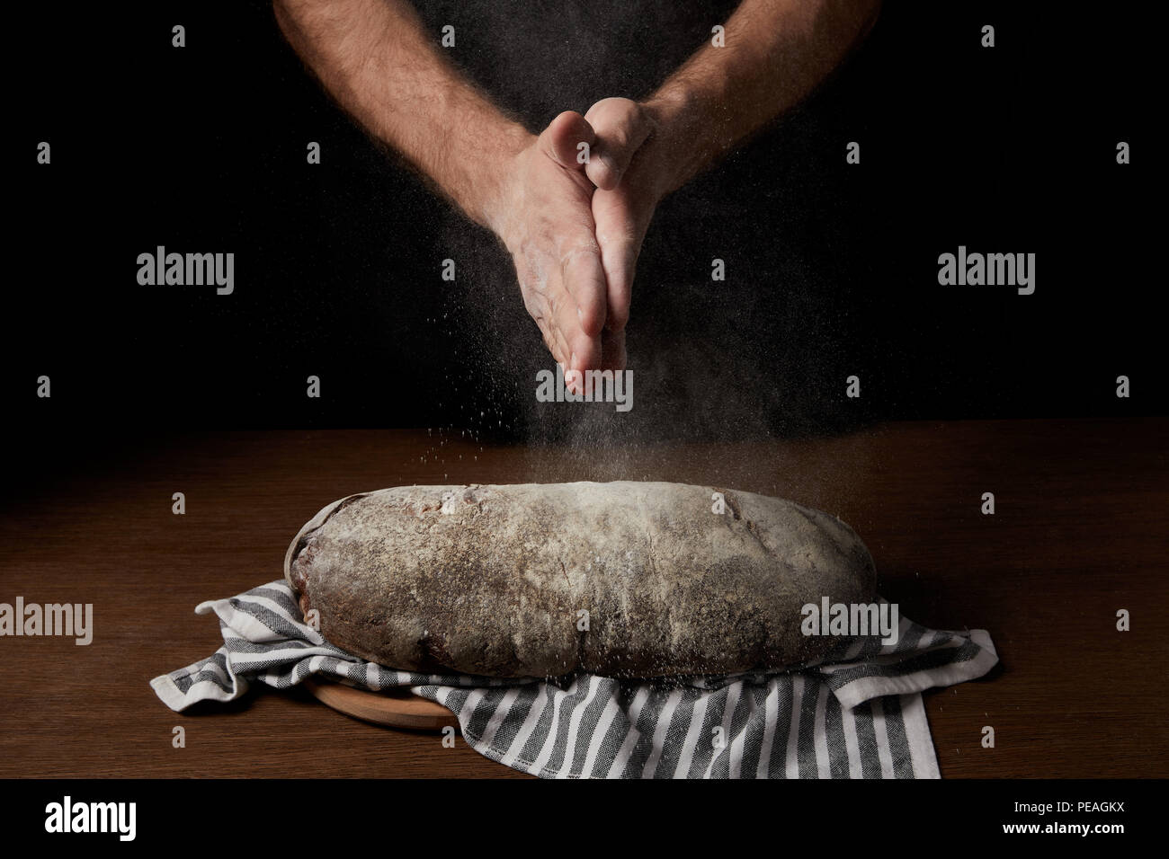 cropped shot of male baker clapping hands with flour over bread on ...