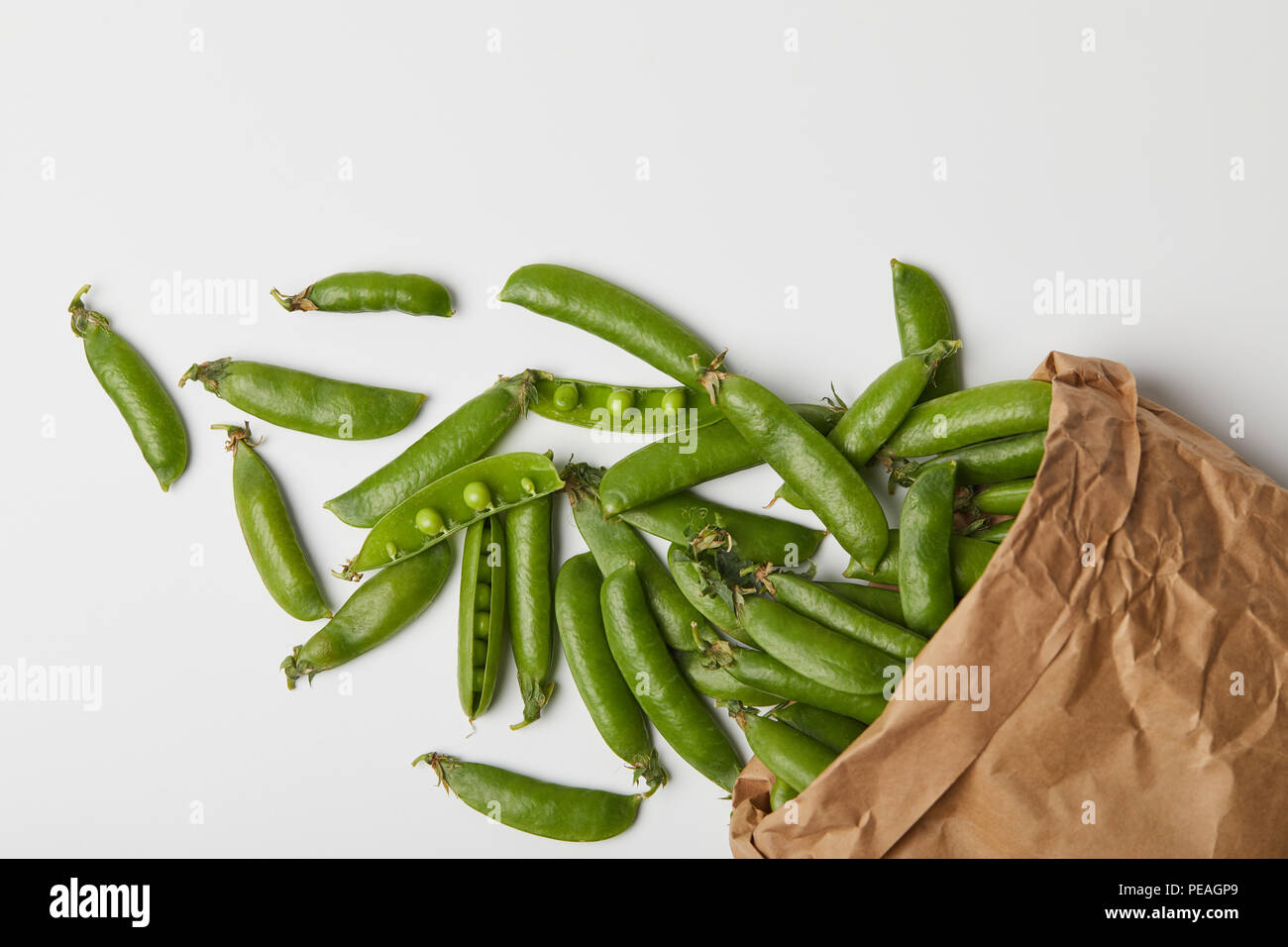 top view of ripe pea pods spilled from paper bag on white surface Stock ...