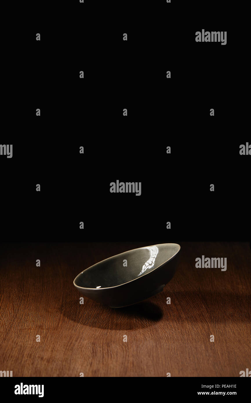 Empty ceramic bowl flying above wooden table surface Stock Photo - Alamy