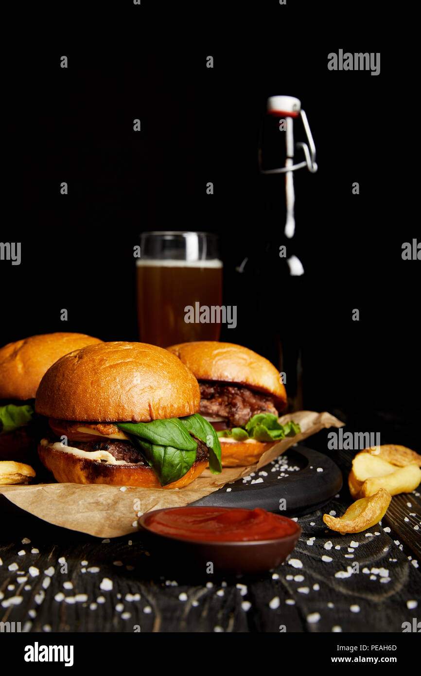Set of junk food hamburgers on table with beer in bottle and glass ...