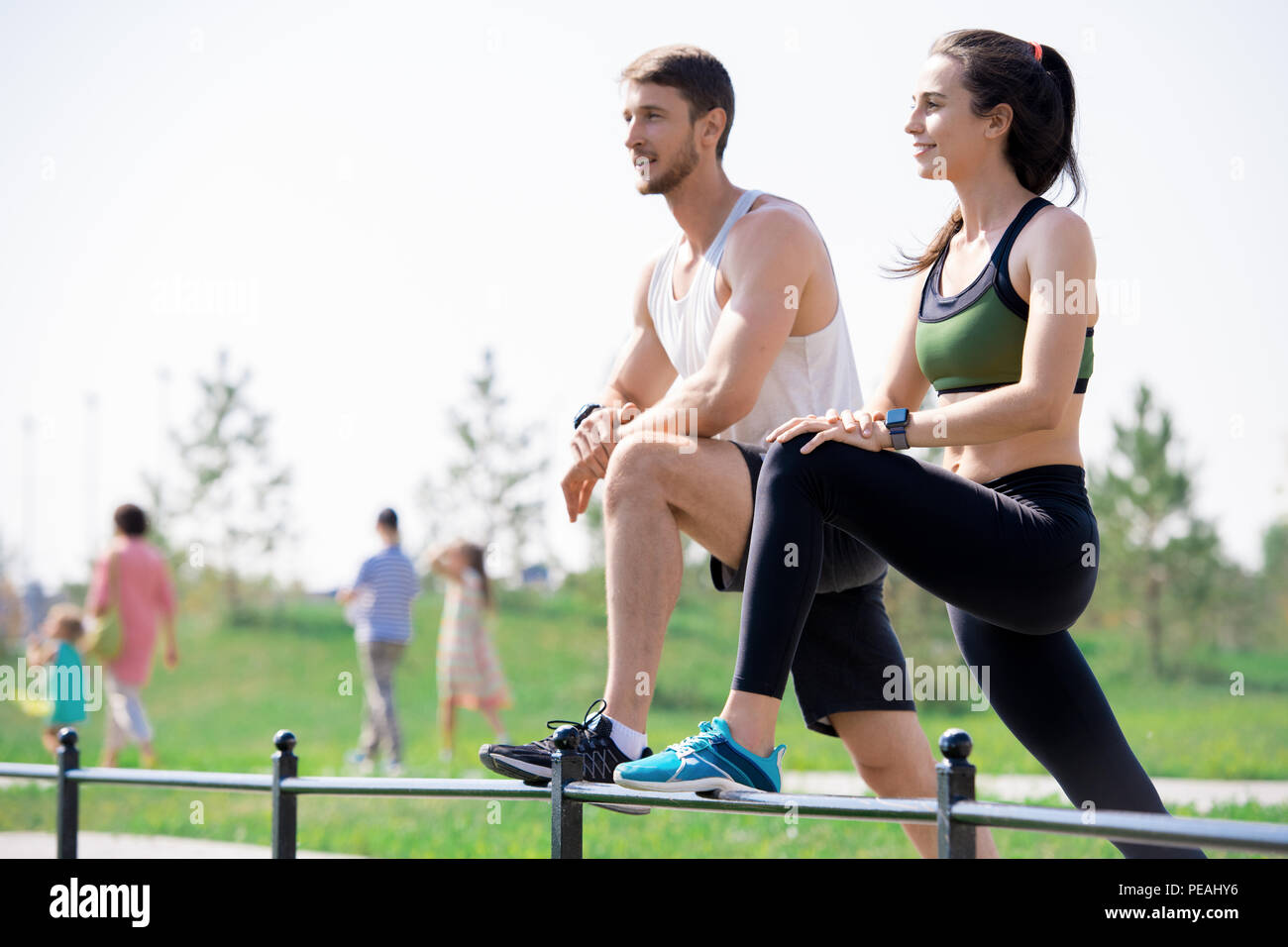 Full length portrait of modern young couple stretching legs while ...