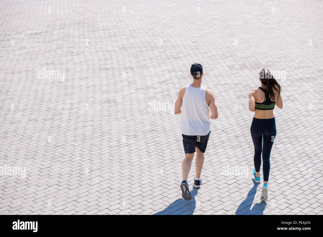 Back view high angle portrait of modern young couple jogging outdoors ...