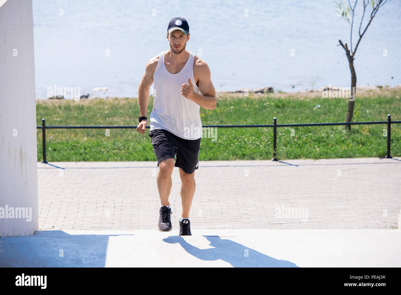 Full length portrait of muscular young man running up and down stair ...