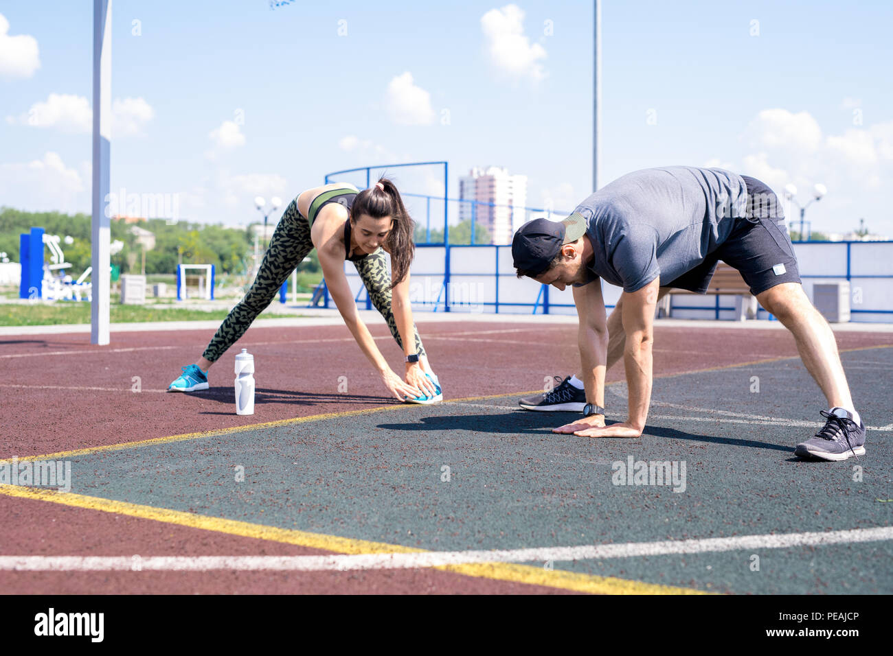 Full length portrait of modern young couple doing stretching exercises ...