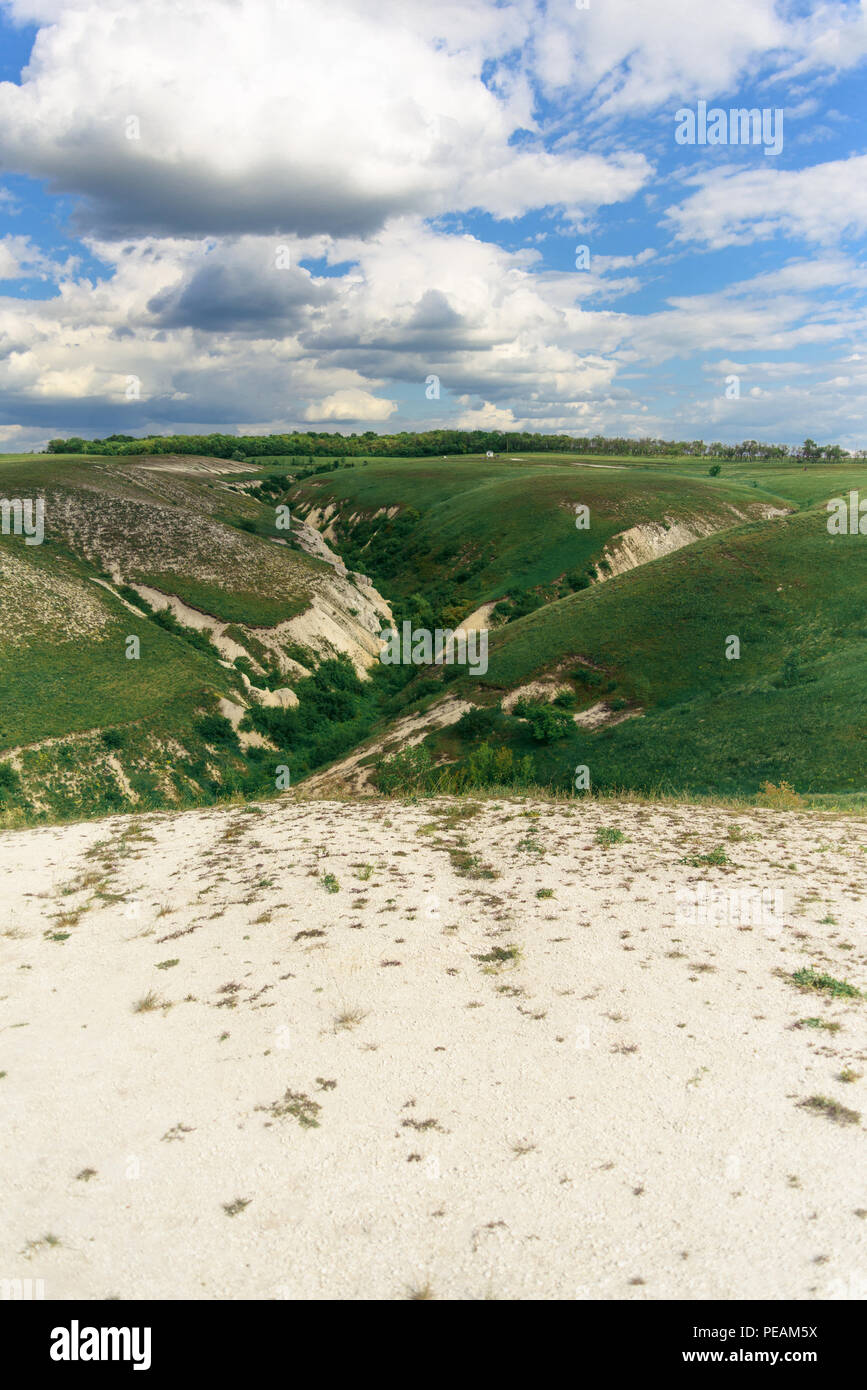 Beautiful view of grassy ravine on sky background with clouds, vertical ...