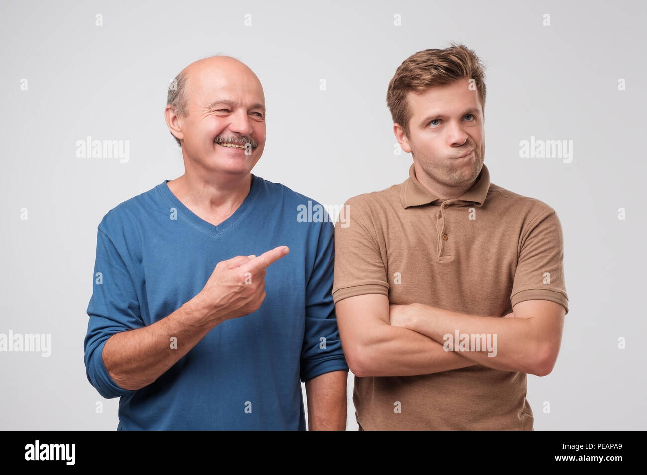 The elderly father laughs at his son. He won the argument. A young man ...