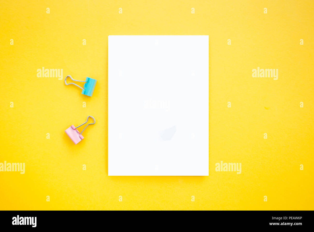 Notepad and binder clips on bright yellow background with copyspace ...