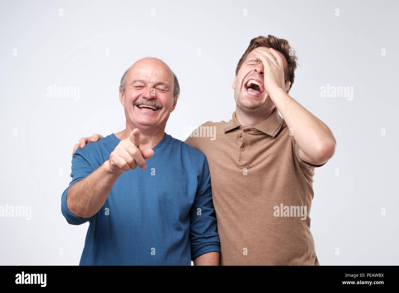 Two friends in casual colorful wear standing and laughing together ...