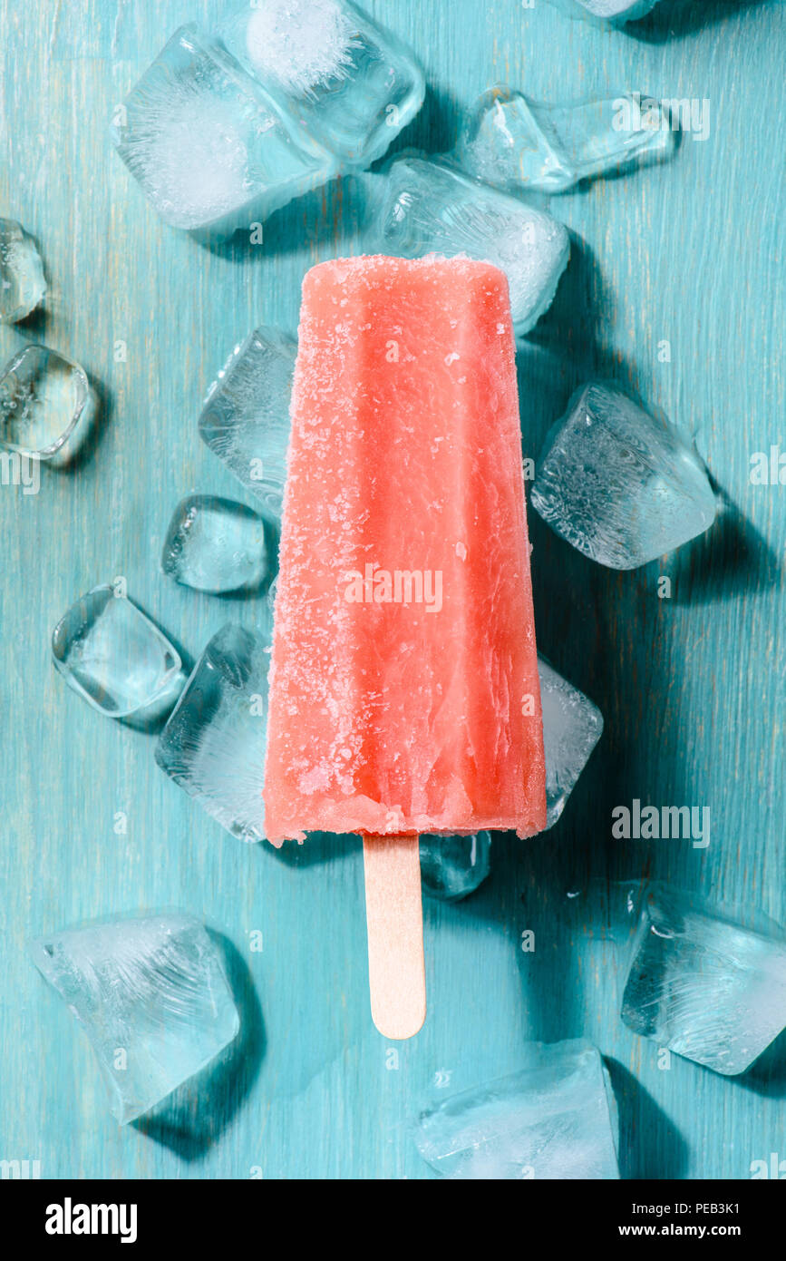 Red fruit ice pop on wooden background with ice cubes Stock Photo - Alamy