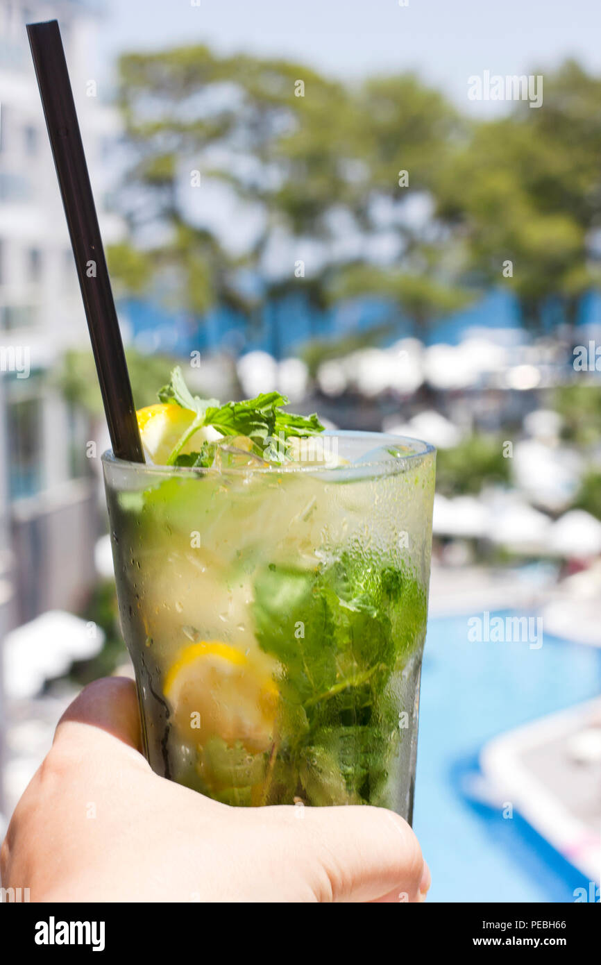 Hand holding Mojito cocktail on the background of a pool Stock Photo ...
