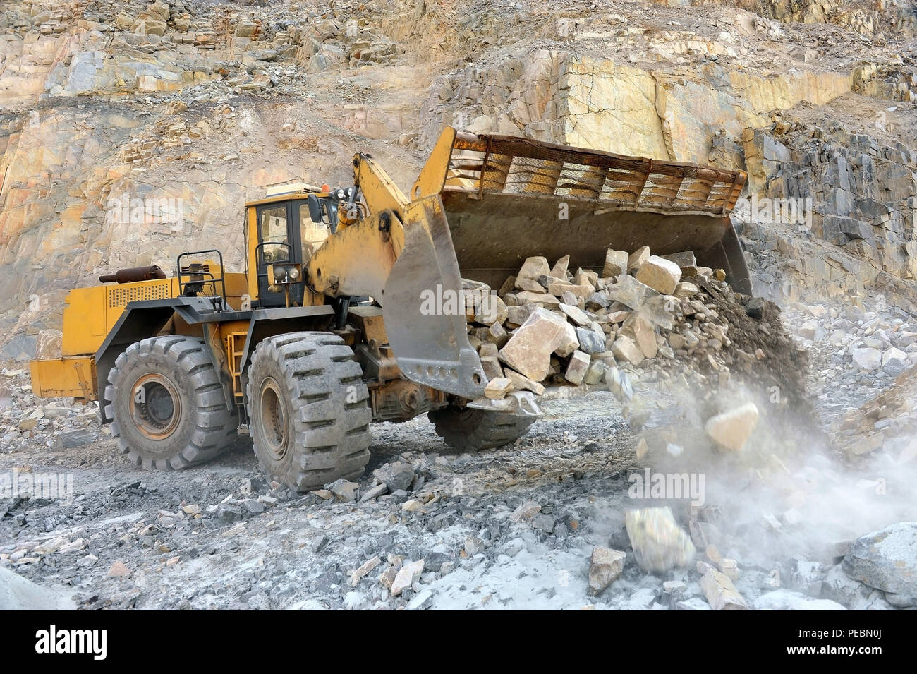 Wheel loader machine unloading rocks in the open-mine of iron ore Stock ...