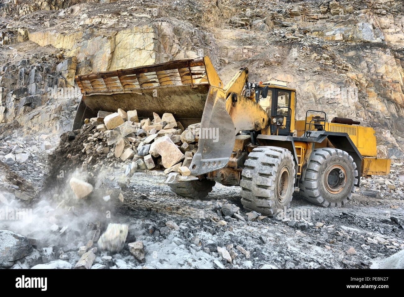 Wheel loader machine unloading rocks in the open-mine of iron ore Stock ...