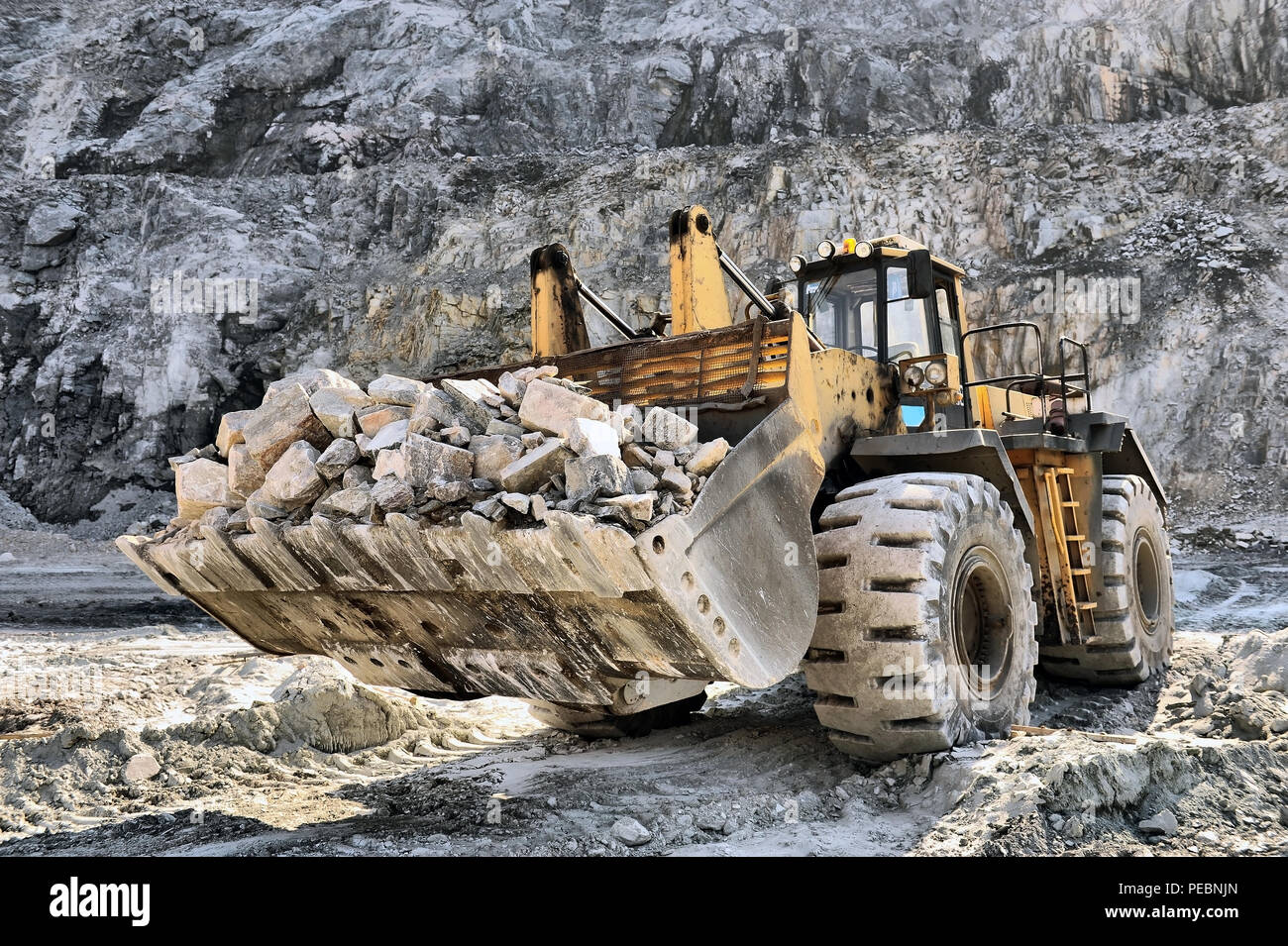 Wheel loader machine unloading rocks in the open-mine of iron ore Stock ...