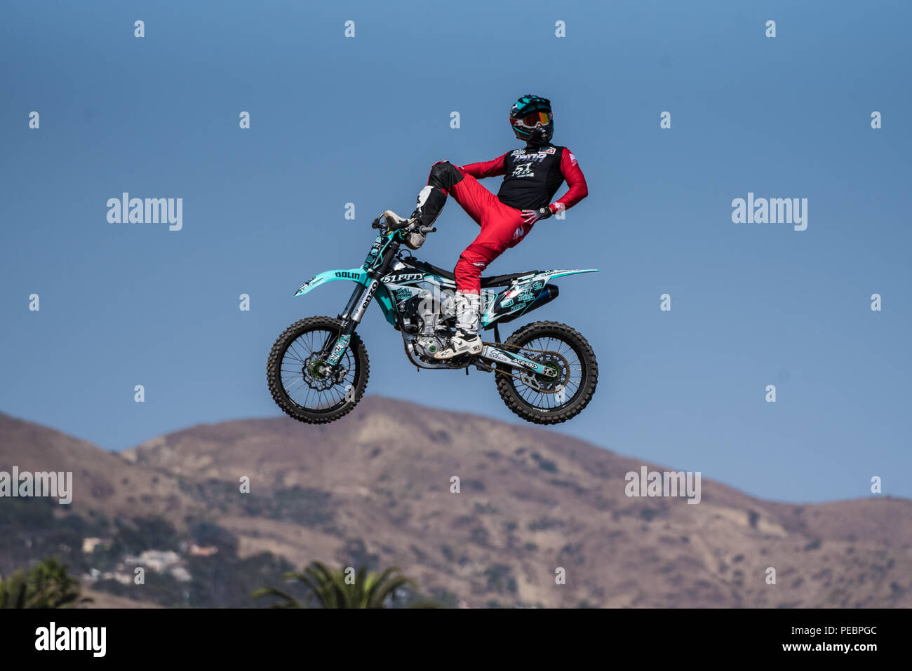 Stunt rider in red costume relaxes with hand on hip and foot on ...