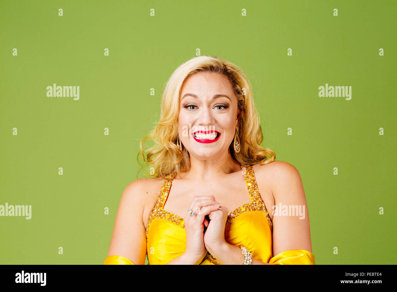 Elegantly dressed blonde woman hoping for something, isolated on green ...