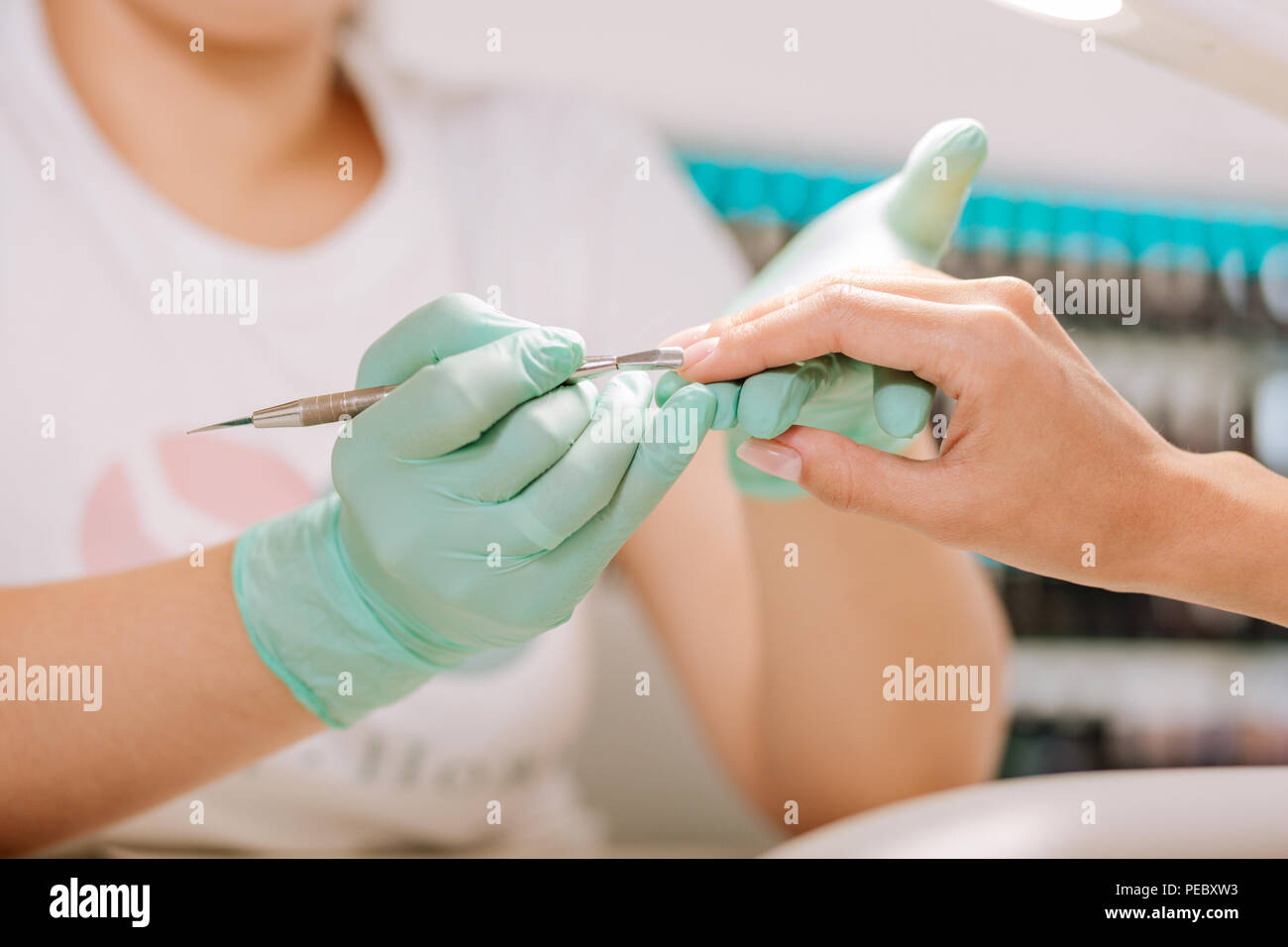 Nail master using manicure tool for removing cuticle Stock Photo - Alamy