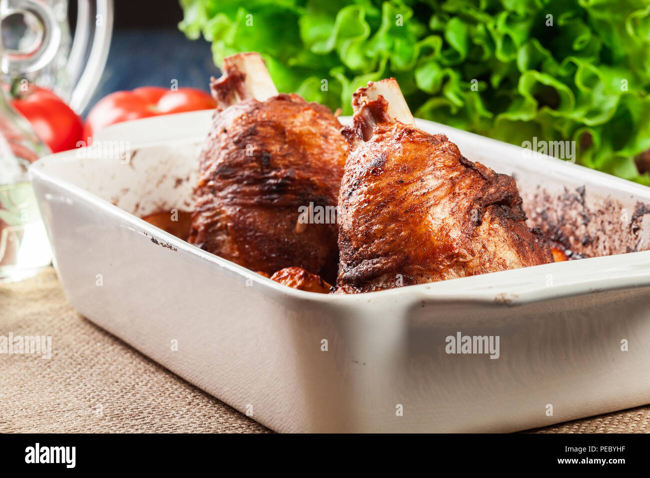 Roasted turkey knuckle with potatoes and vegetable in the baking dish ...