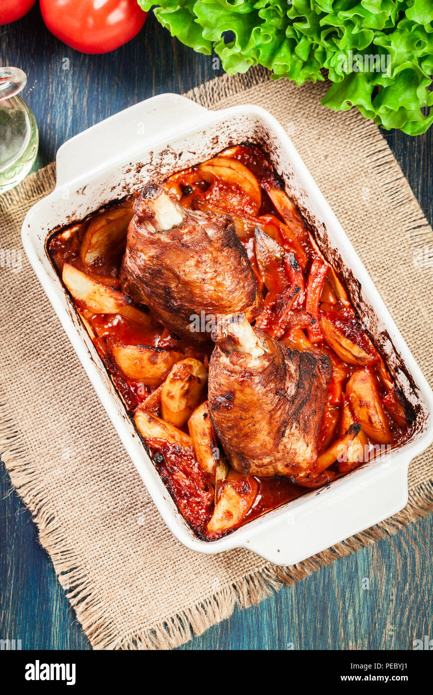 Roasted turkey knuckle with potatoes and vegetable in the baking dish ...