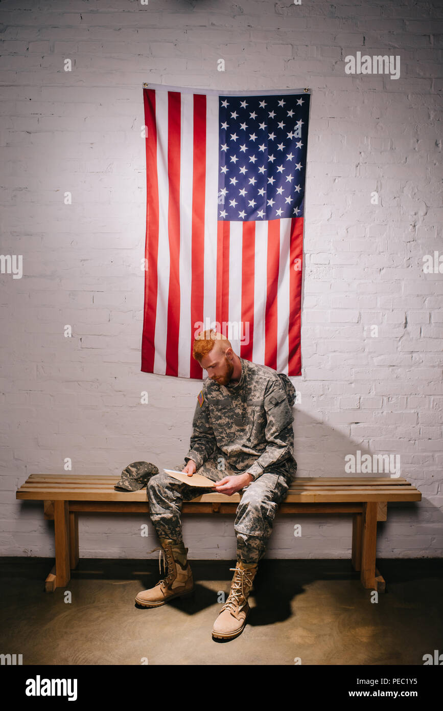 red hair american soldier with letter sitting on wooden bench with flag ...