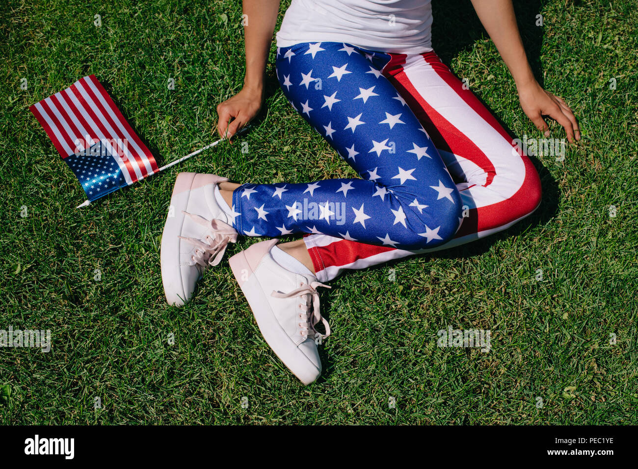 partial view of woman with flagpole in leggins with american flag ...