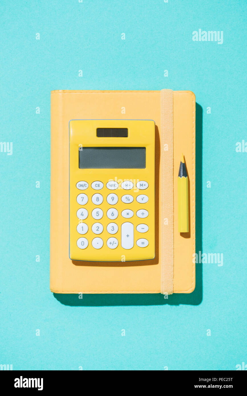 top view of arrangement of calculator, pencil and notebook on blue ...