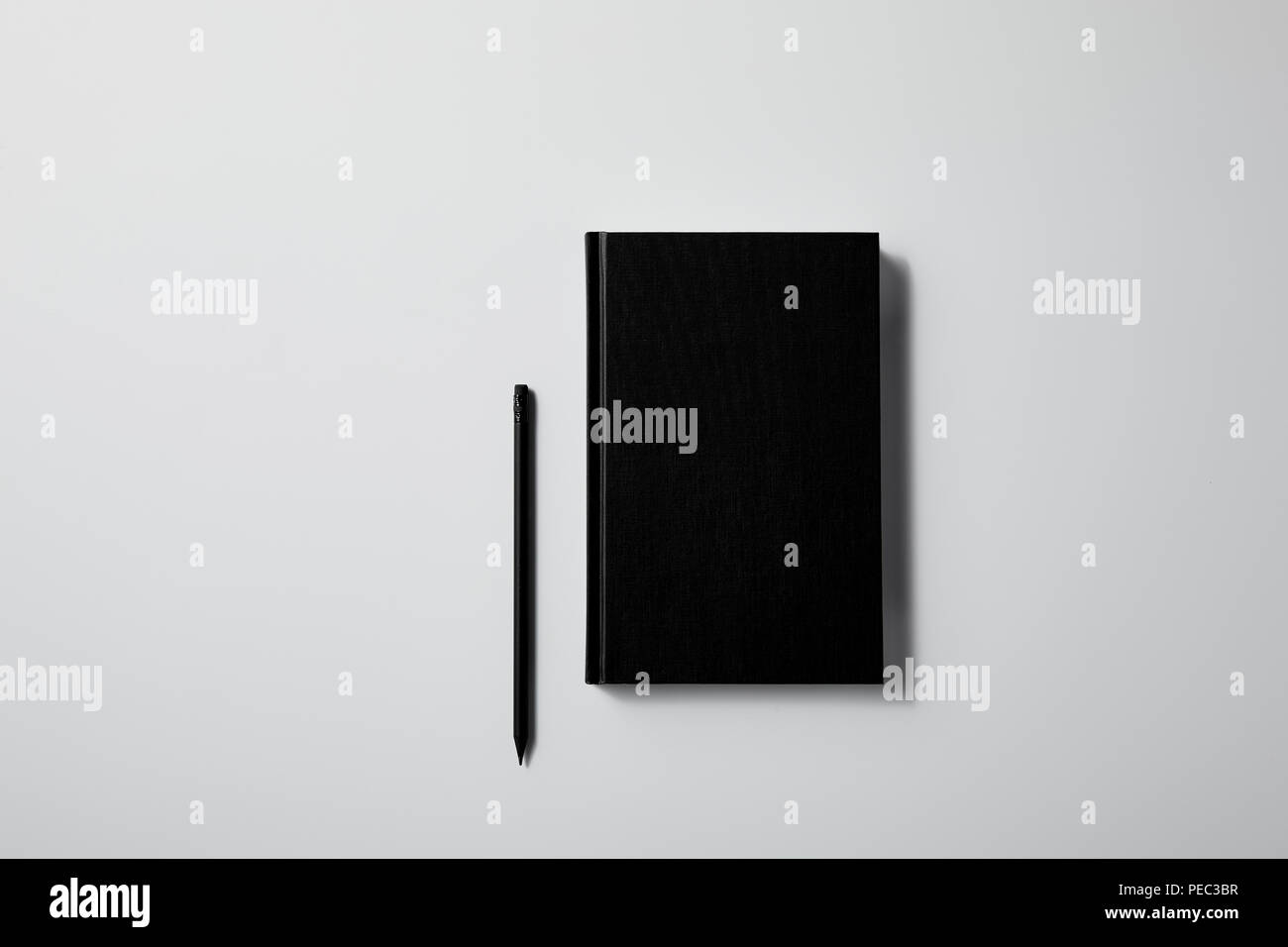top view of black notebook with pencil on white surface for mockup ...