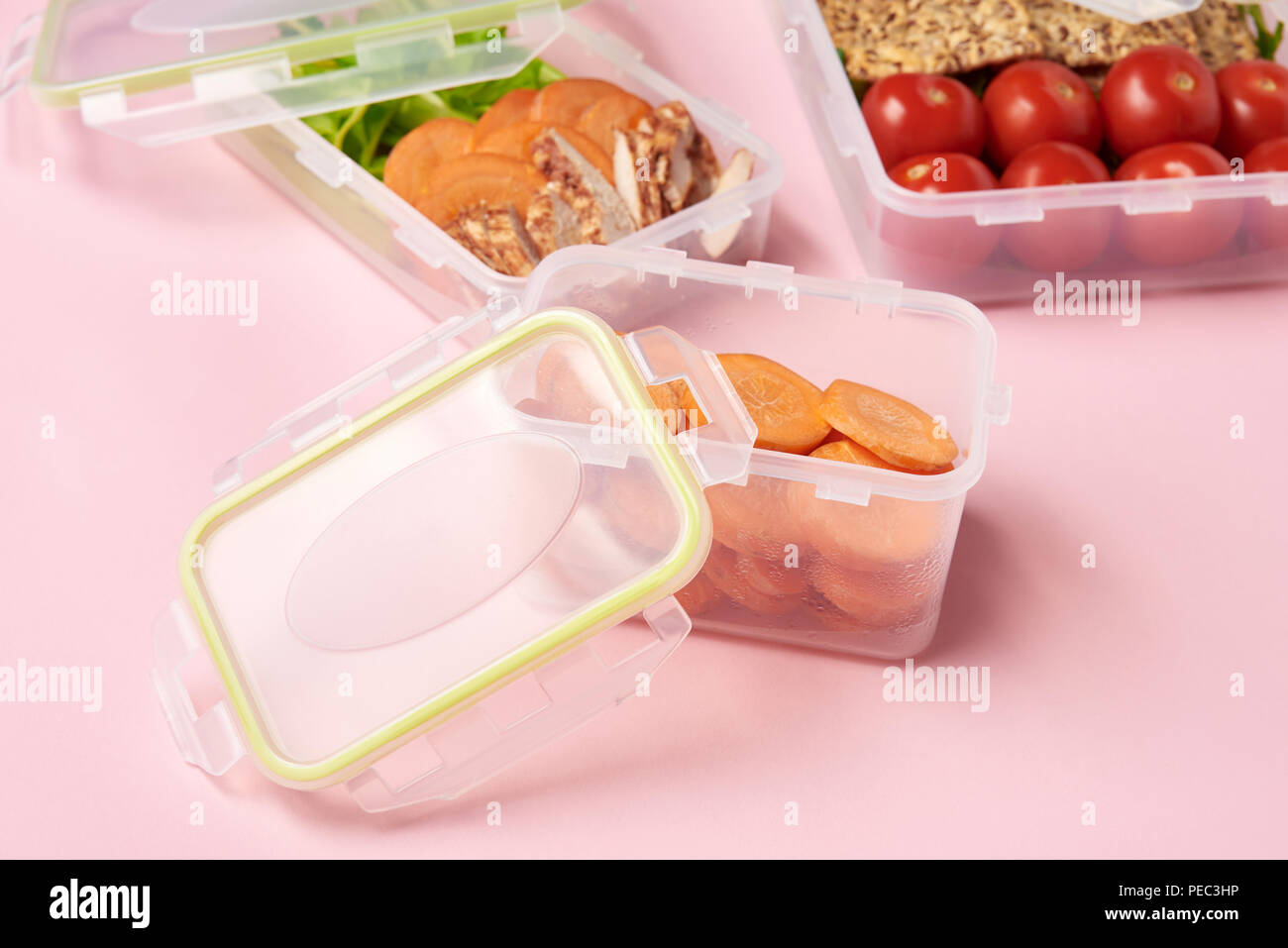 close up view of healthy food arranged in food containers on pink ...