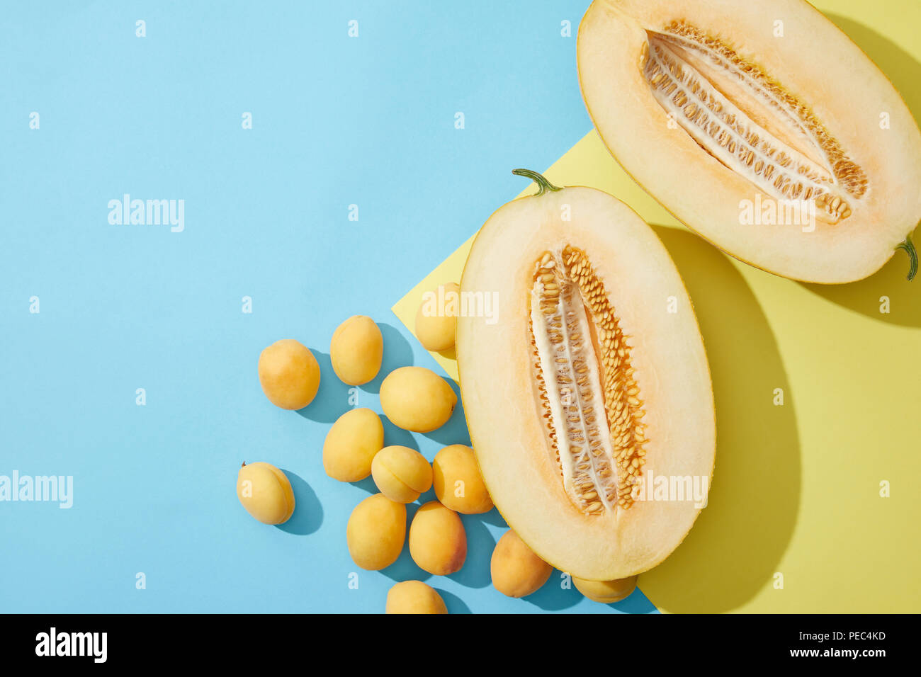 top view of fresh sweet apricots and halved melon on blue and yellow ...