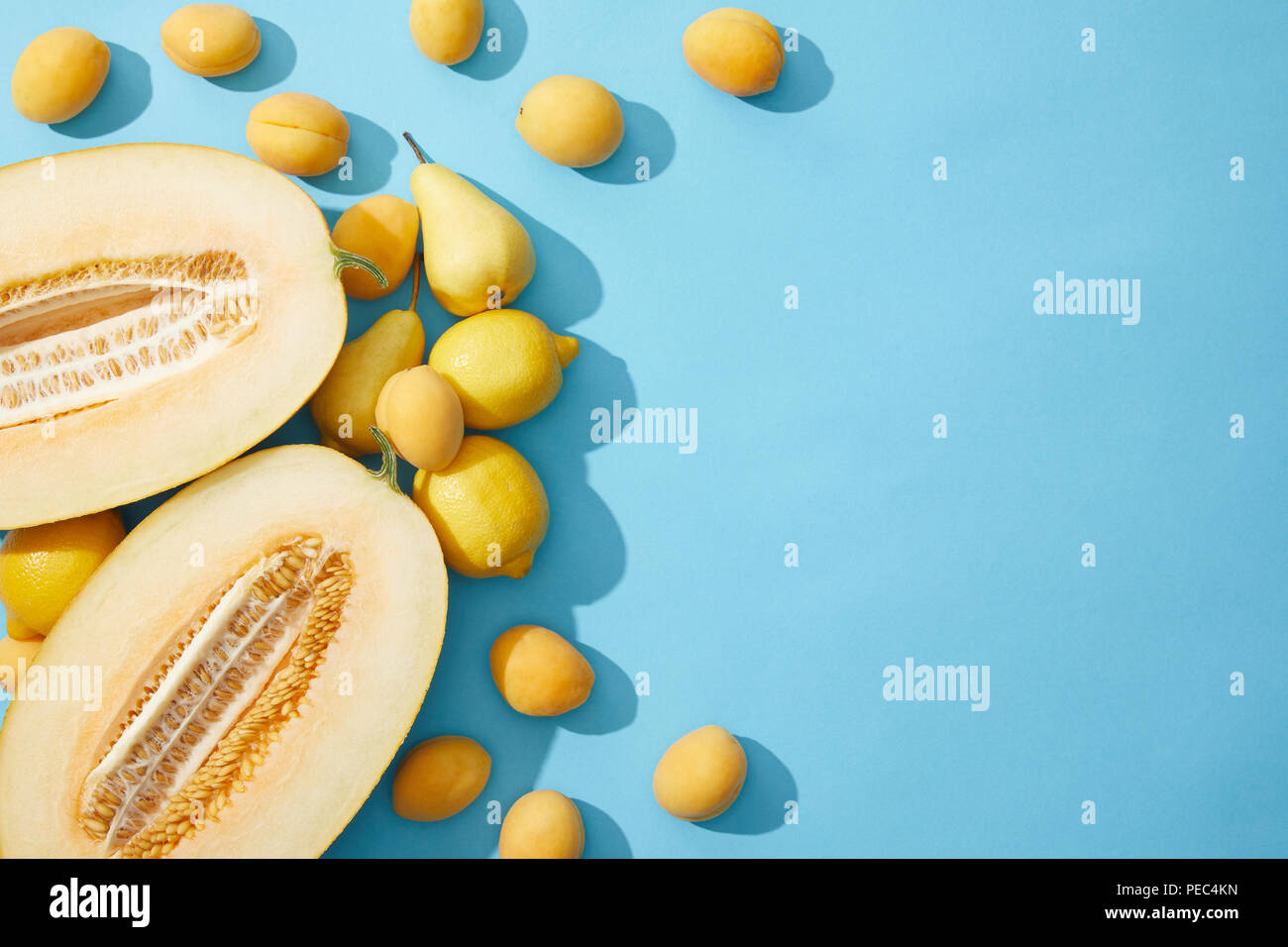 top view of fresh ripe melon, pears, lemons and apricots on blue ...