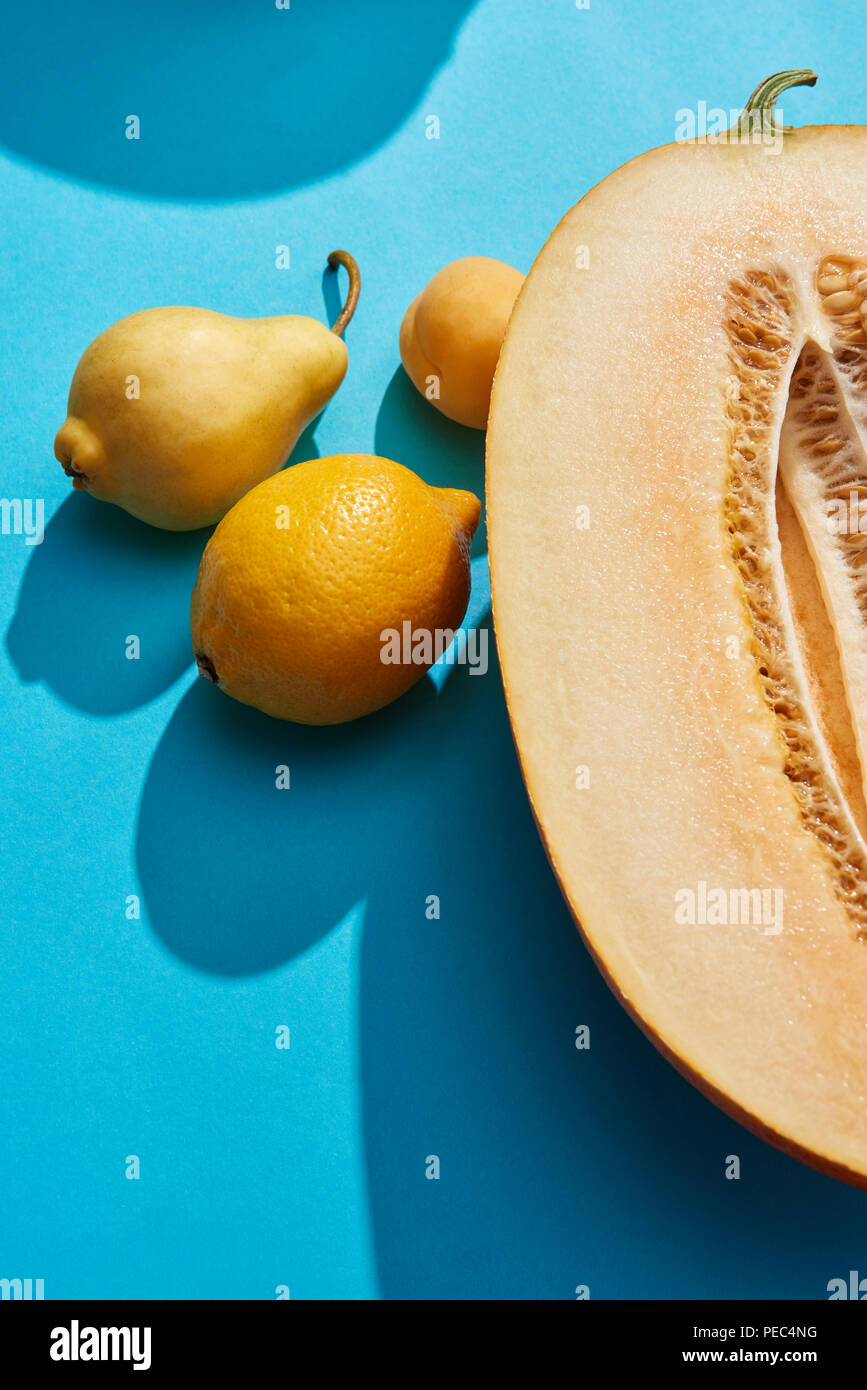 close-up view of fresh ripe melon, pear, apricot and lemon on blue ...