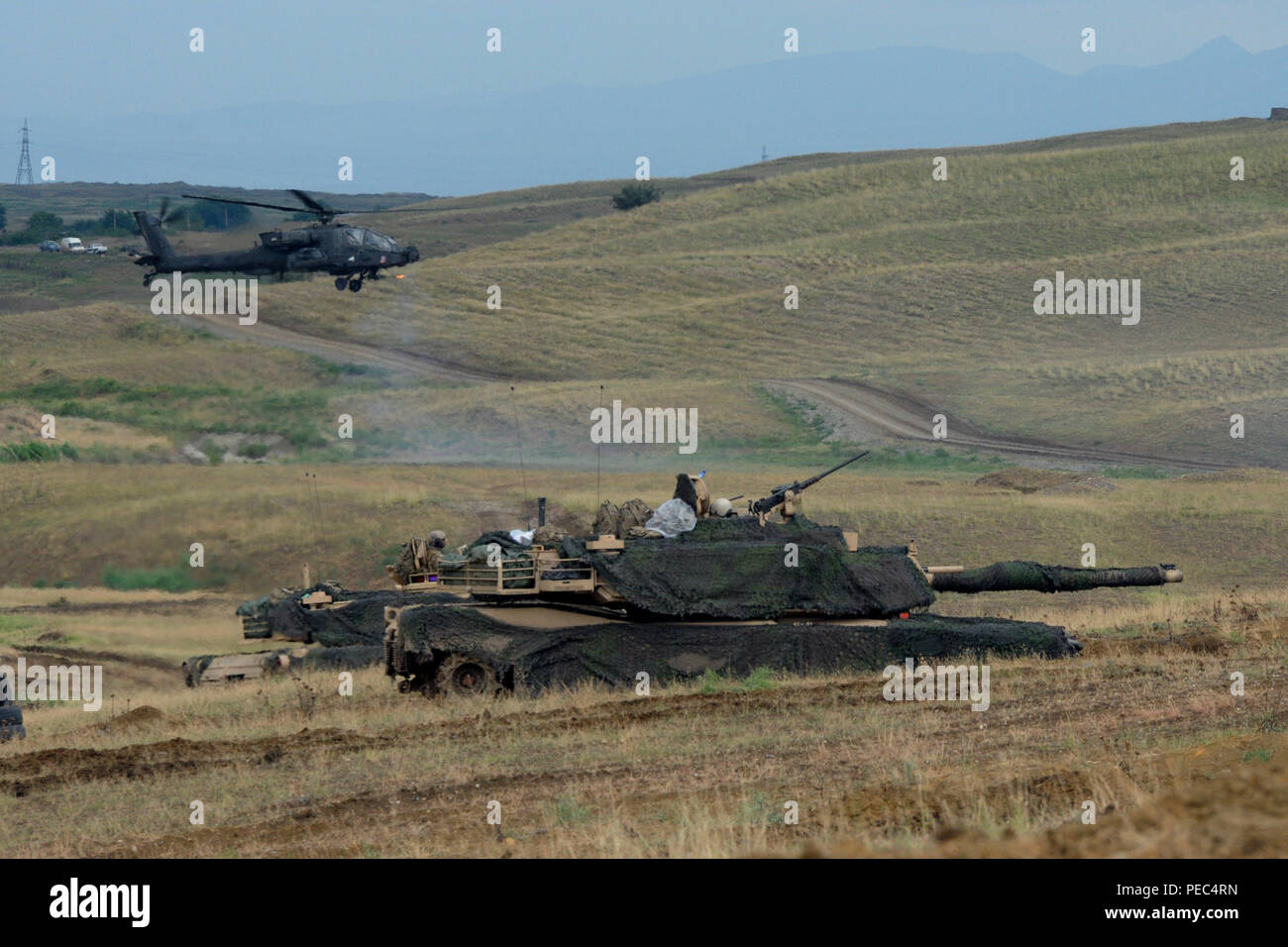An AH-64 Apache attack helicopter fires as M1A2 Abrams tanks assigned ...