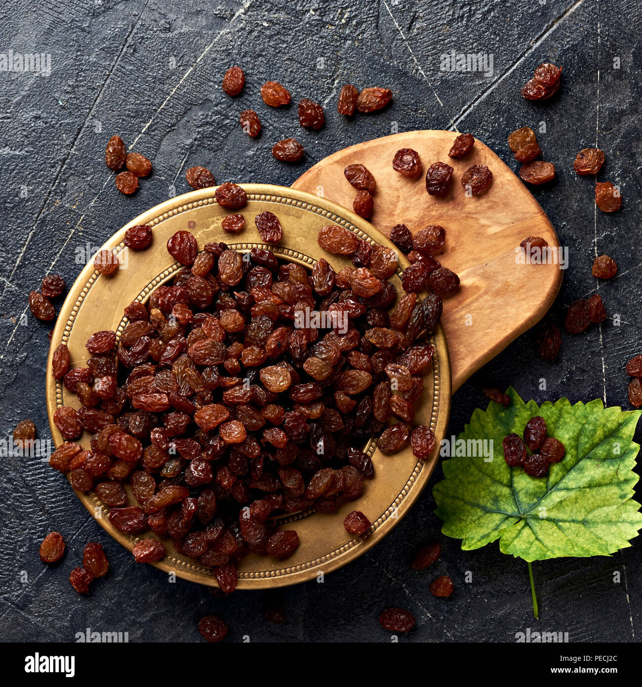 Heap of brown raisins on plate. Top view of dried grapes with green ...