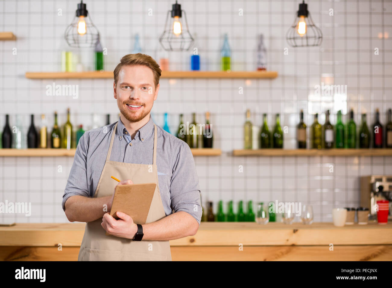 Professional waiter. Delighted nice handsome man standing in front of ...