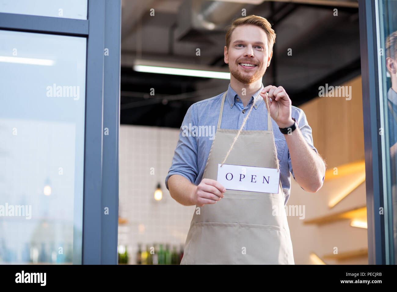 Visit our place. Happy good looking friendly waiter standing near the ...