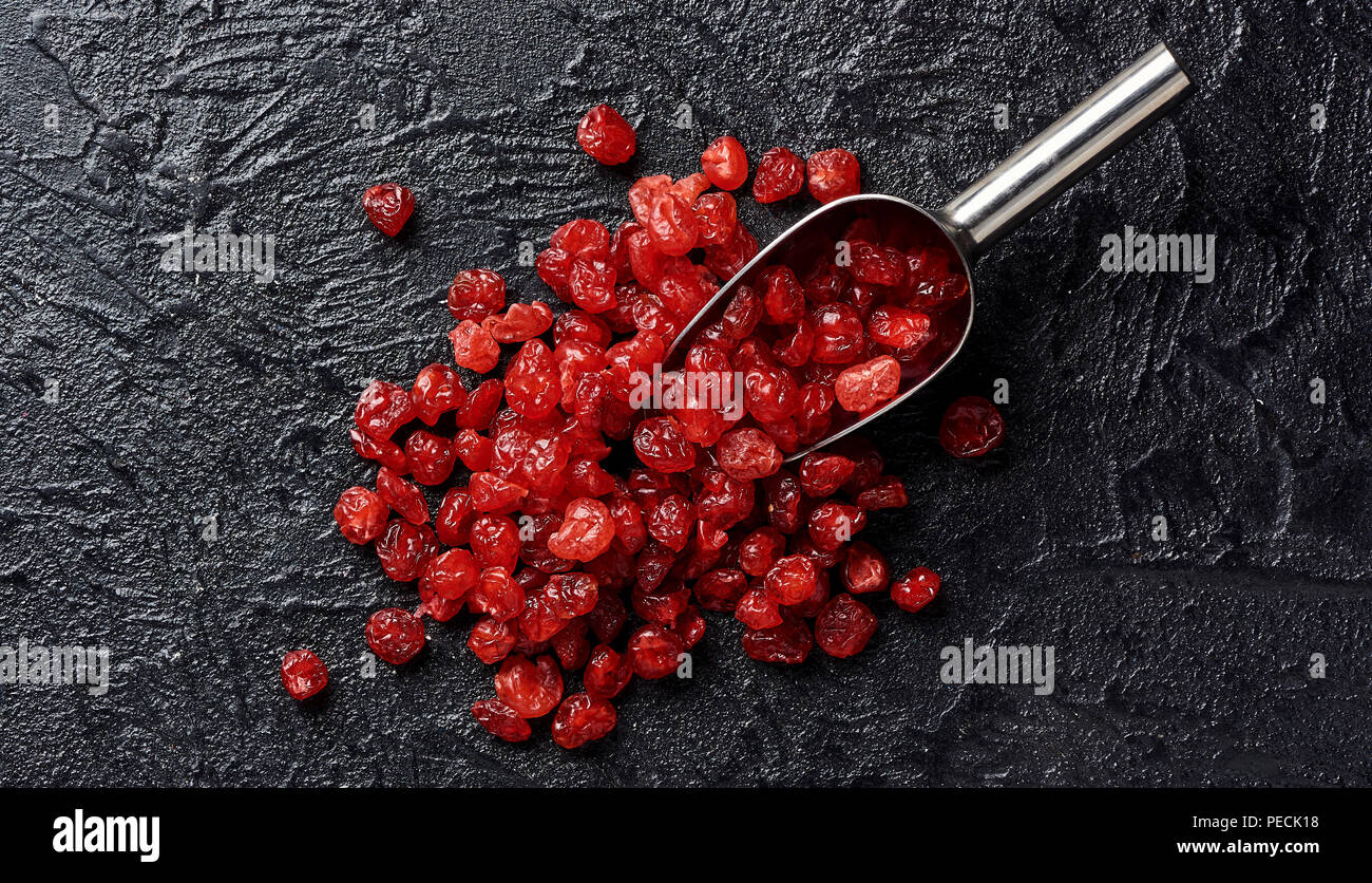 Dried red cherries on a black background with scoop Stock Photo - Alamy