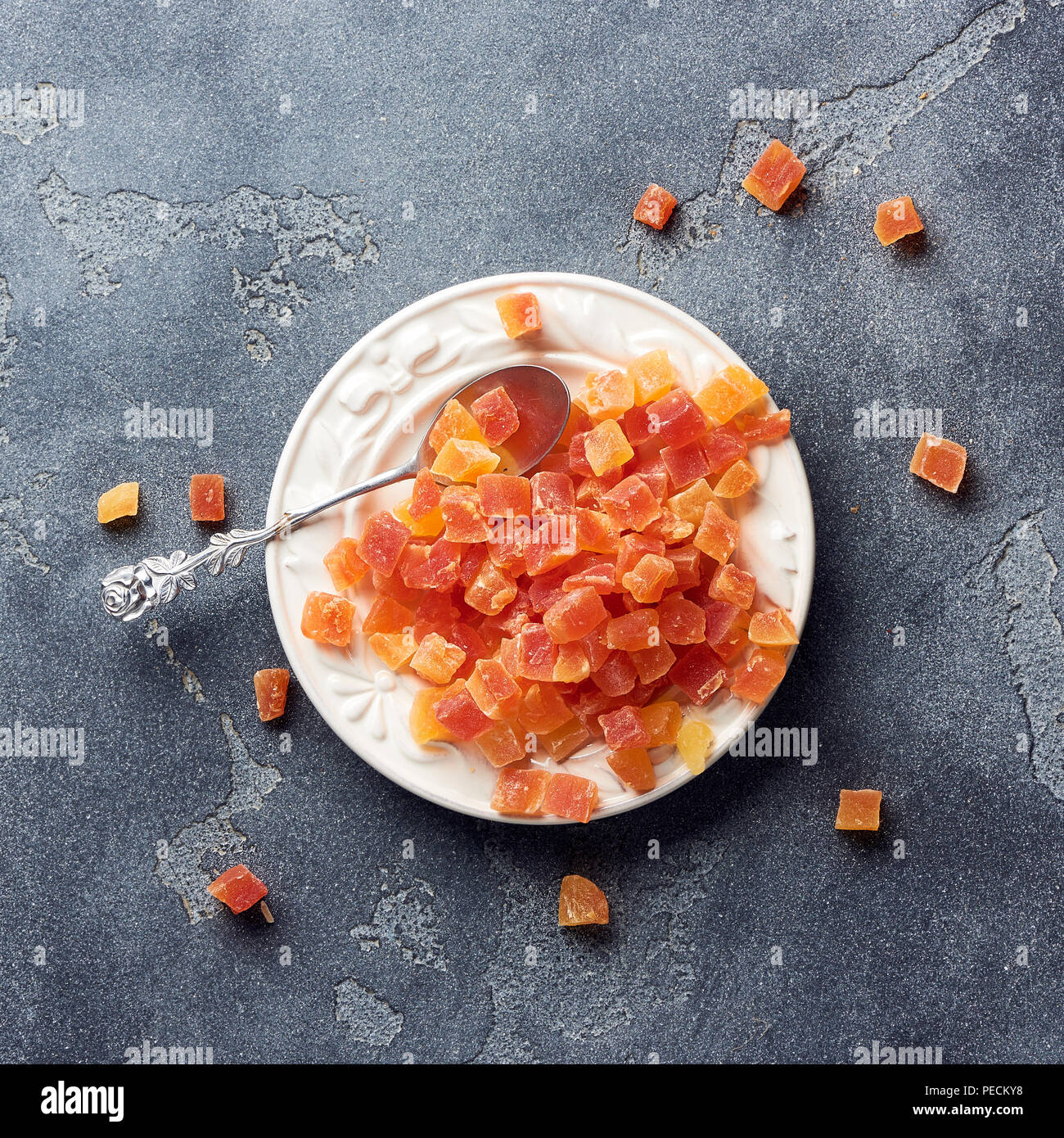 Cubes of dried apricot, mango and papaya on white palte. Candied fruits ...