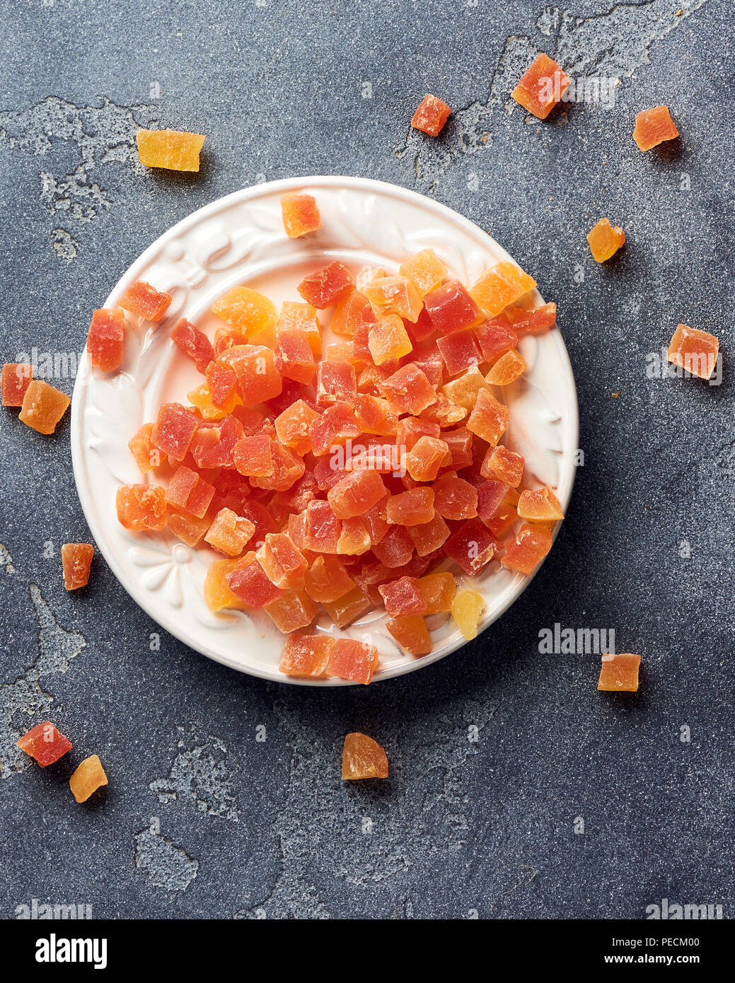 Cubes of dried apricot, mango and papaya on white palte. Candied fruits ...
