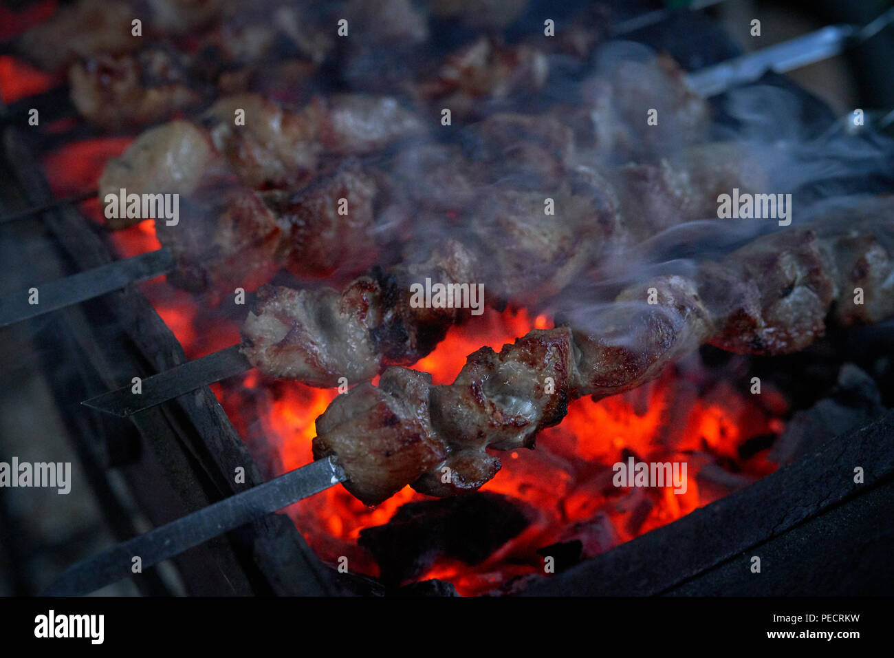 Shashlik preparing on a barbecue grill over charcoal. Pieces of meat on ...