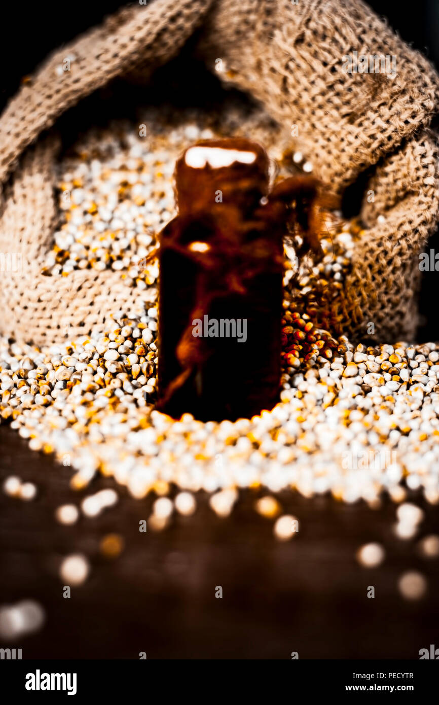 Close up of pearl millet oil with raw pearl millet on a wooden surface ...