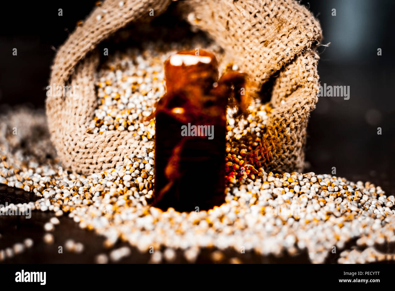 Close up of pearl millet oil with raw pearl millet on a wooden surface ...