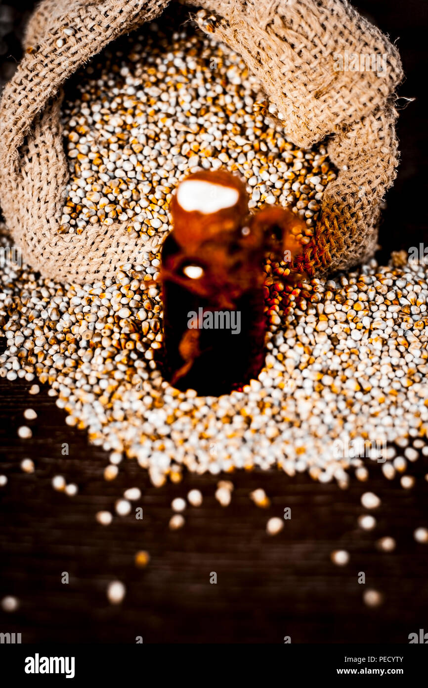 Close up of pearl millet oil with raw pearl millet on a wooden surface ...