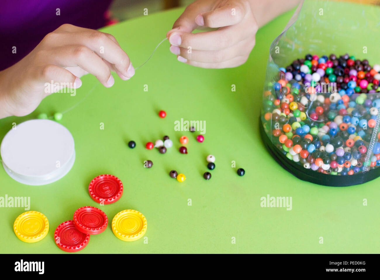 Girl's hand stringing beads on a string Stock Photo - Alamy