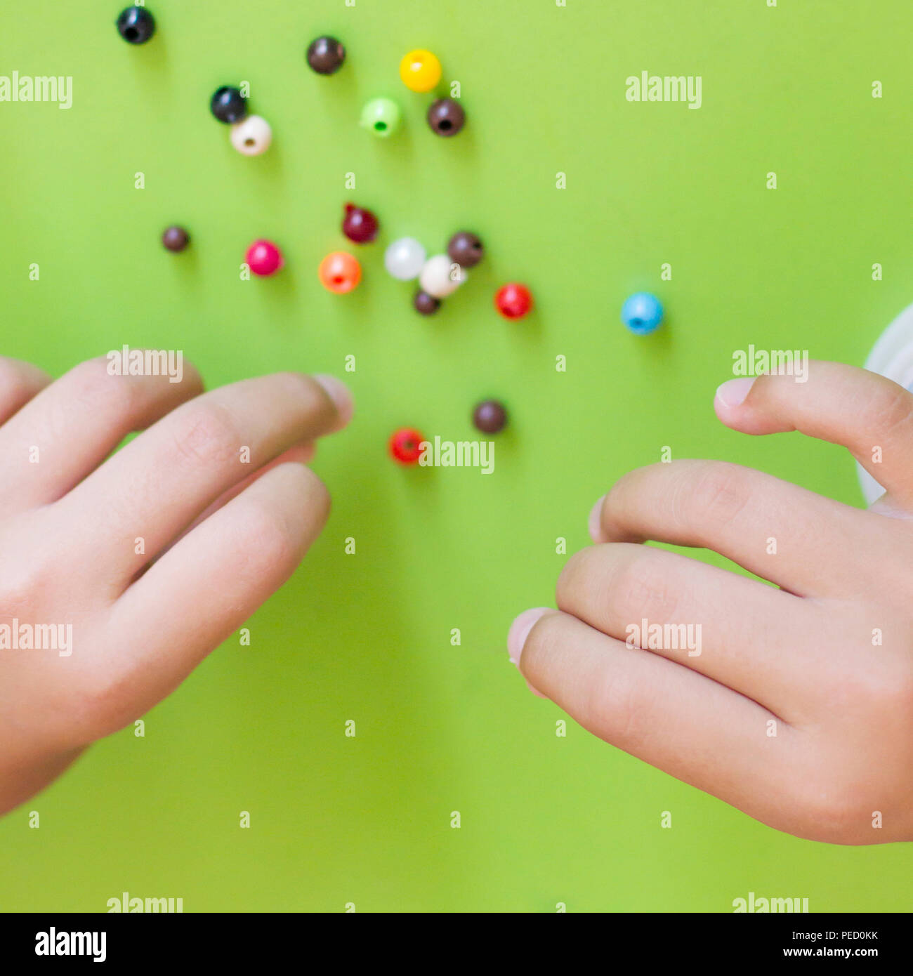 Girl's hand stringing beads on a string Stock Photo - Alamy