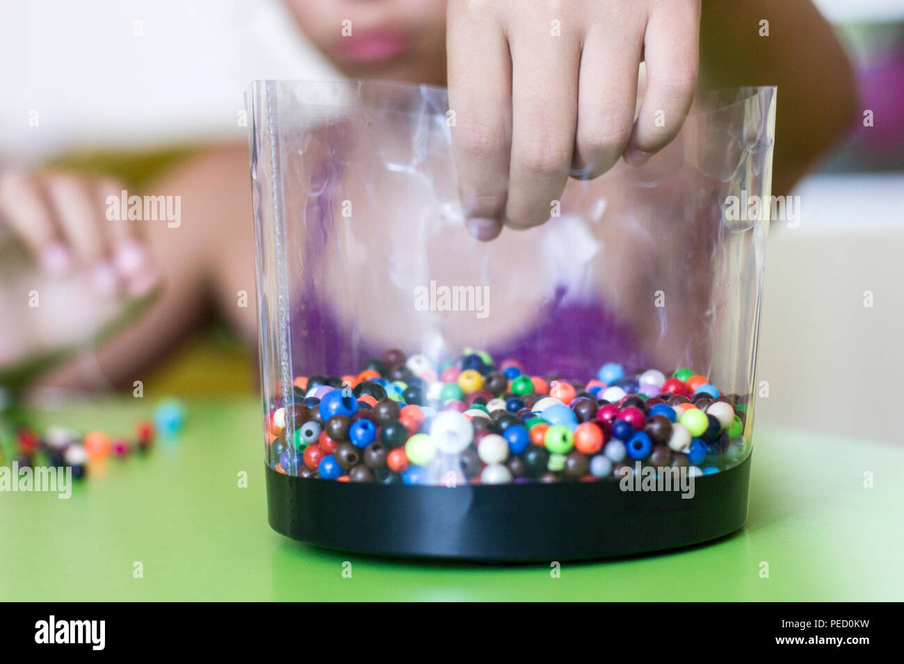 Girl's hand stringing beads on a string Stock Photo - Alamy