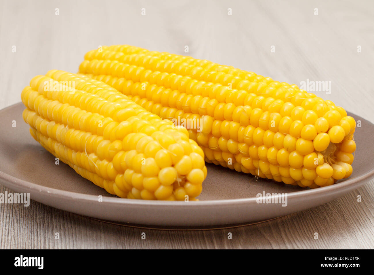Starts of cooked corn on porcelain plate with grey wooden boards on the ...